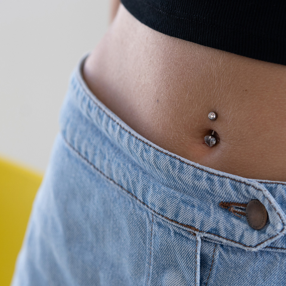 Elegantes Bauchnabelpiercing mit einem süßen Steinherz