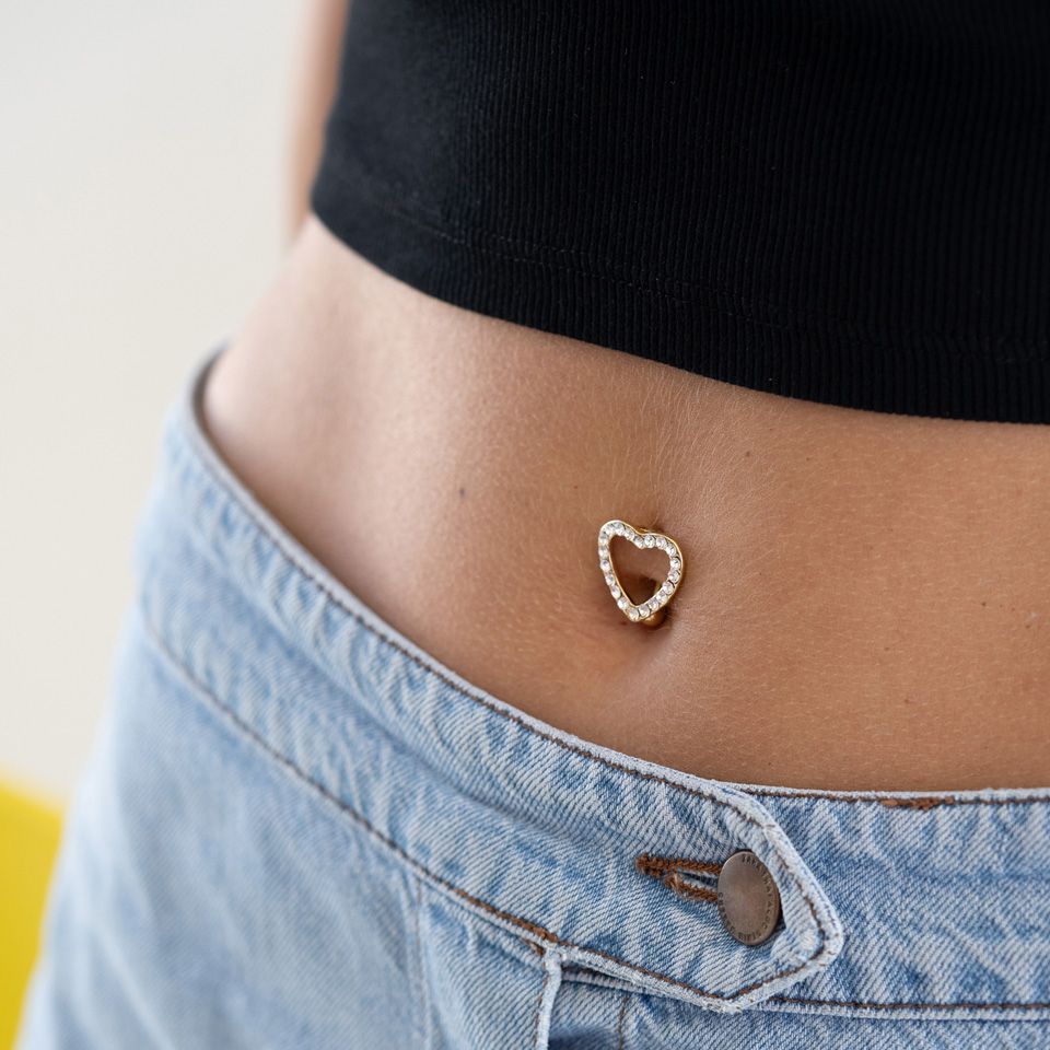Funkelndes Bauchnabelpiercing mit einem großen Herz und Steinen